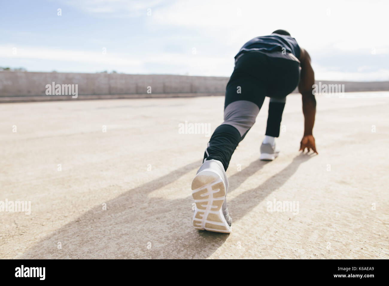 Athlete man in running start pose on the city street. Sport tight ...