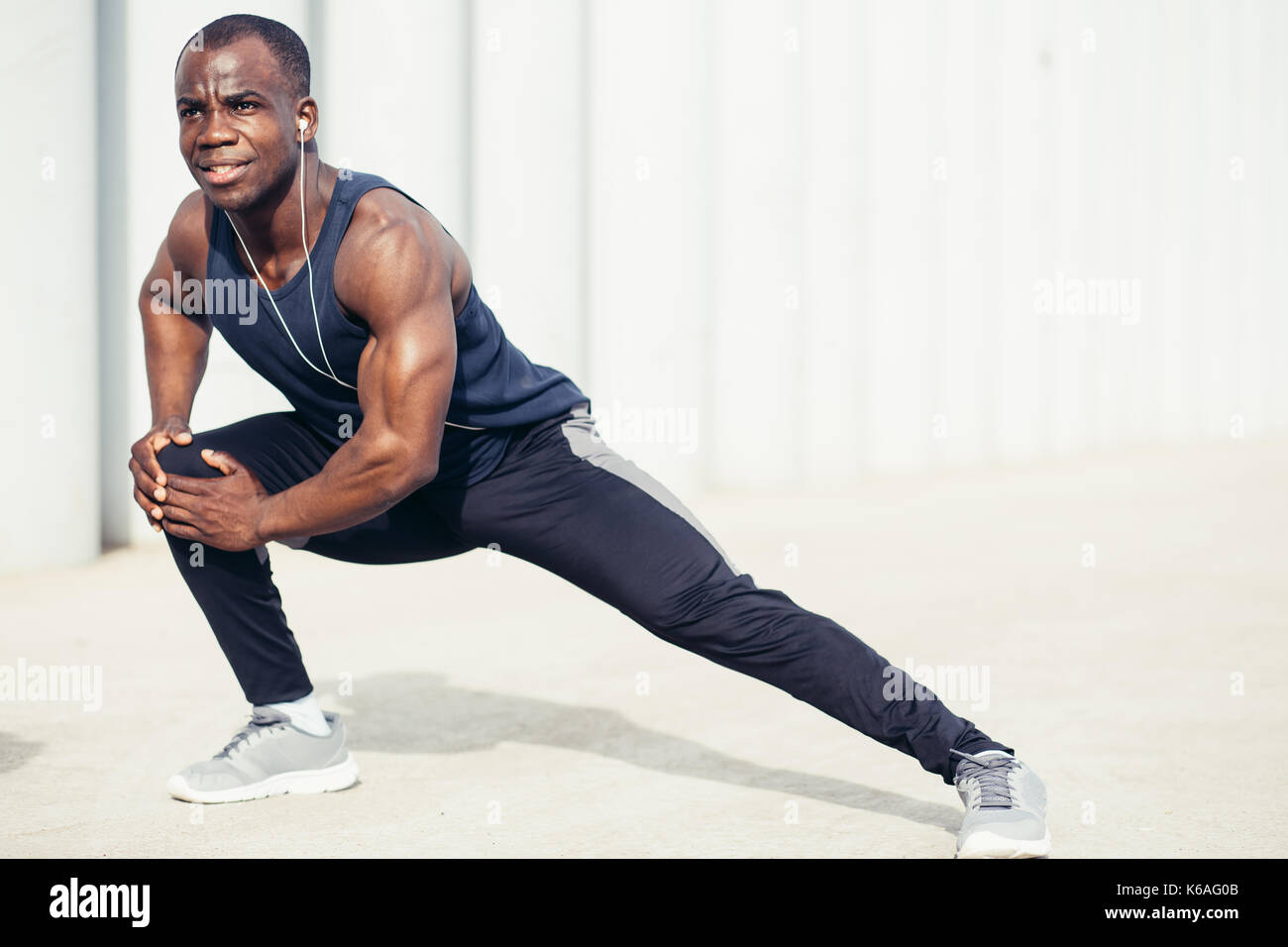 Black man doing stretching before running in urban background. Young ...