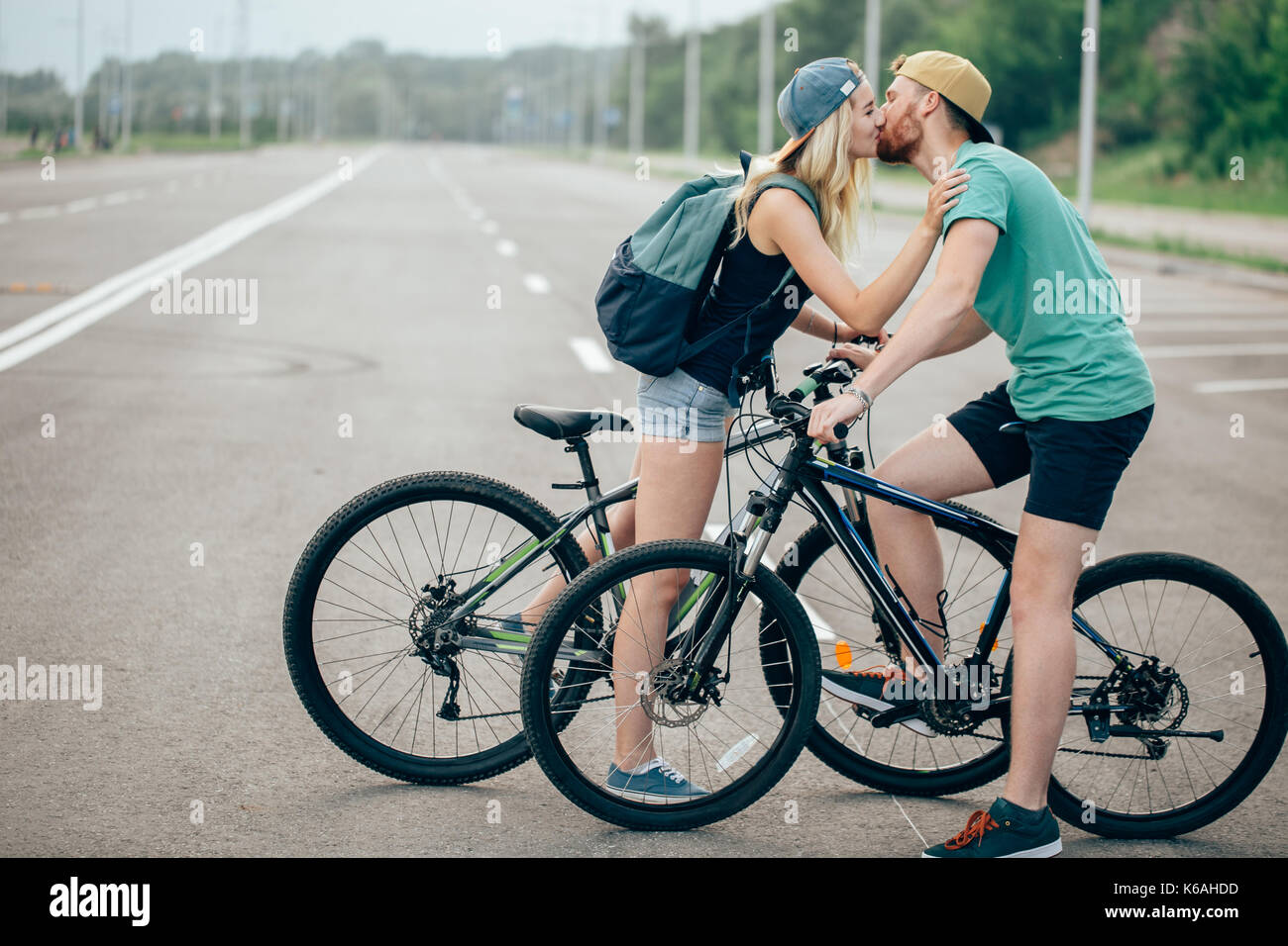 Beautiful young couple in love walking with bicycles, kissing and ...