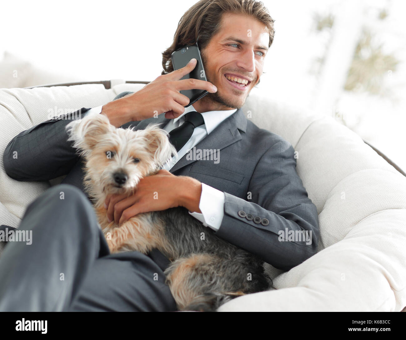 successful businessman holds his dog and pet and talks on the ...