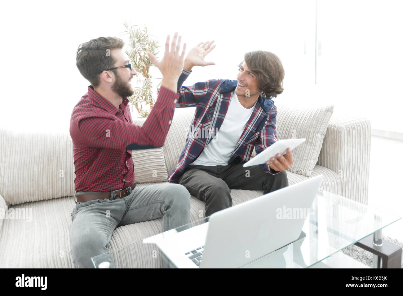 wo guys sitting on the couch and giving each other five Stock Photo - Alamy