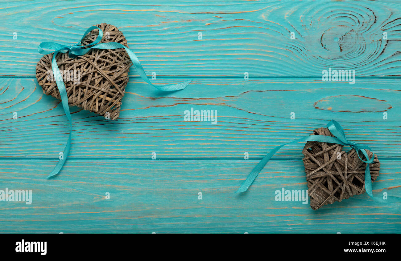Decorative wicker hearts of gray color with a blue ribbon on a wooden background. Top view Stock ...