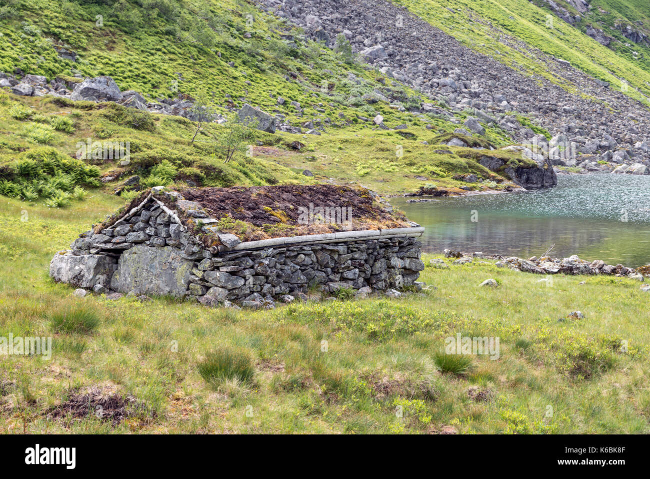 very old hut house build from stacked stones an plants on the roof at a ...