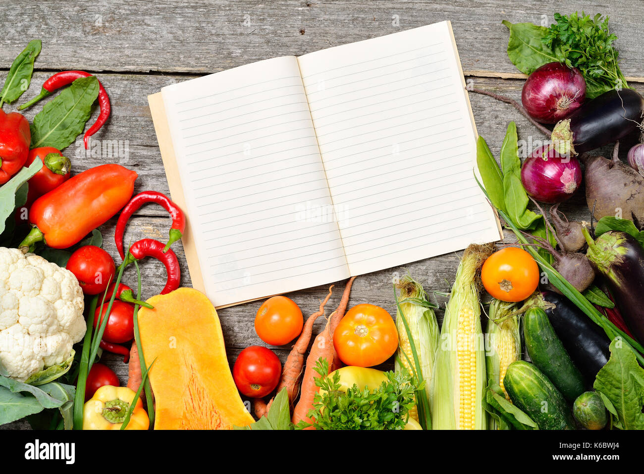 Open recipe book with set of raw organic vegetables on vintage wooden ...