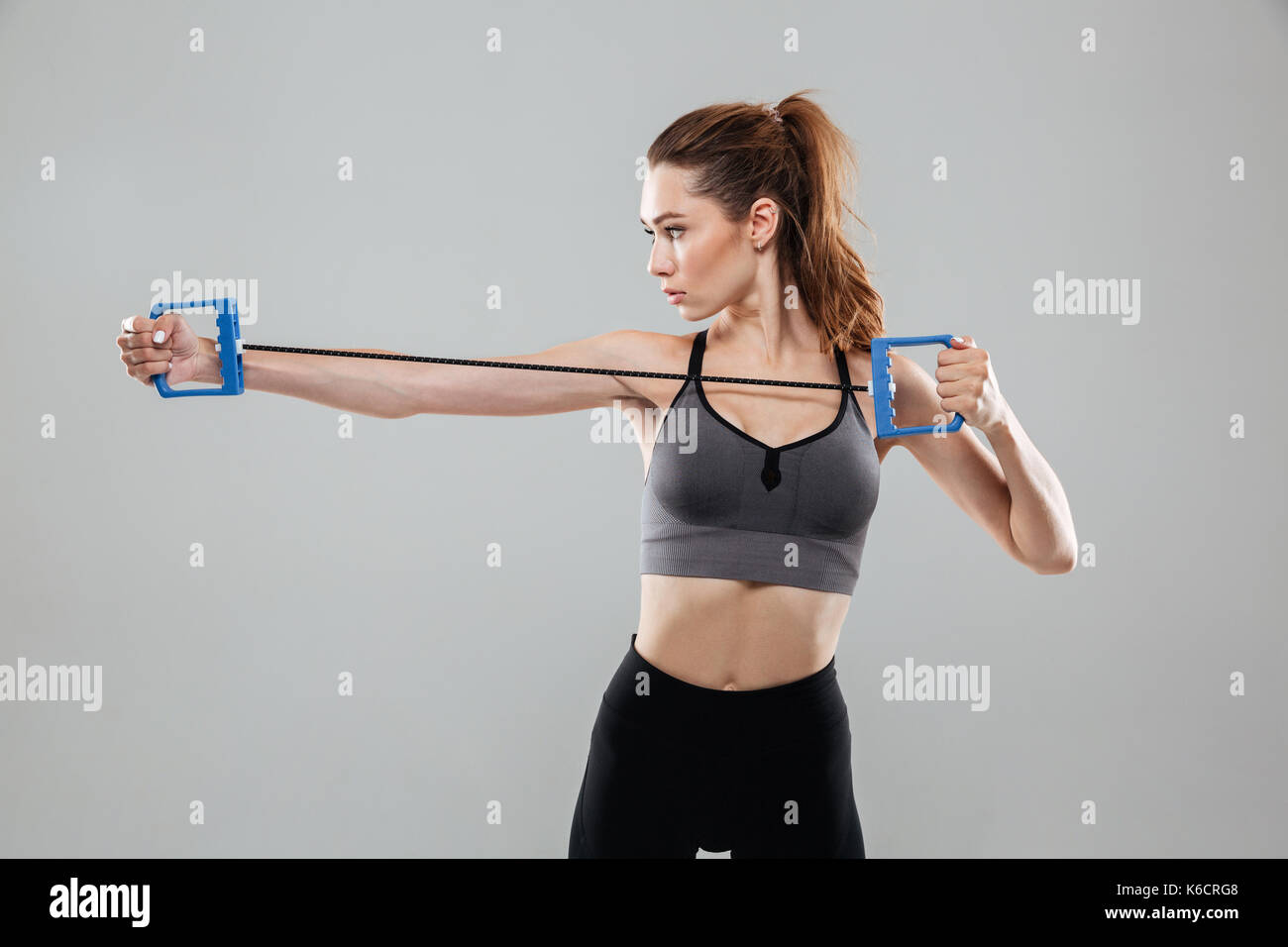 Side view of a sports woman doing exercises with hand expander over ...