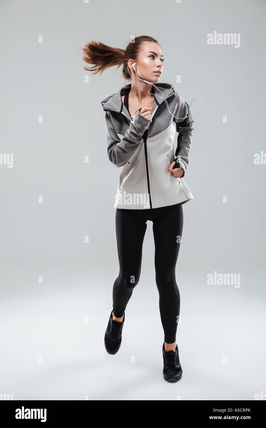 Full length picture of a attractive female runner running in studio and ...