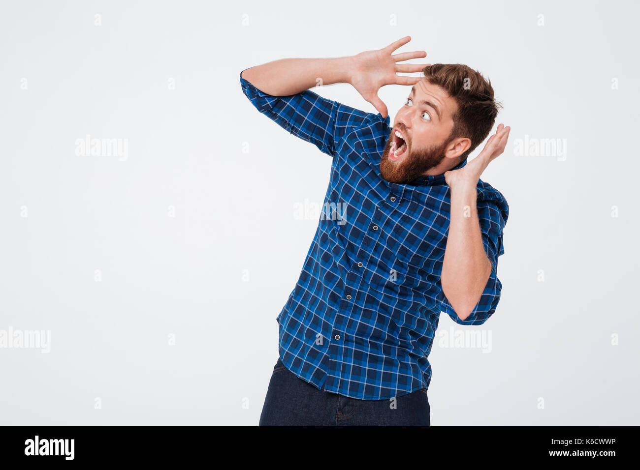 Shocked bearded man scaring and screaming while looking at copyspace ...