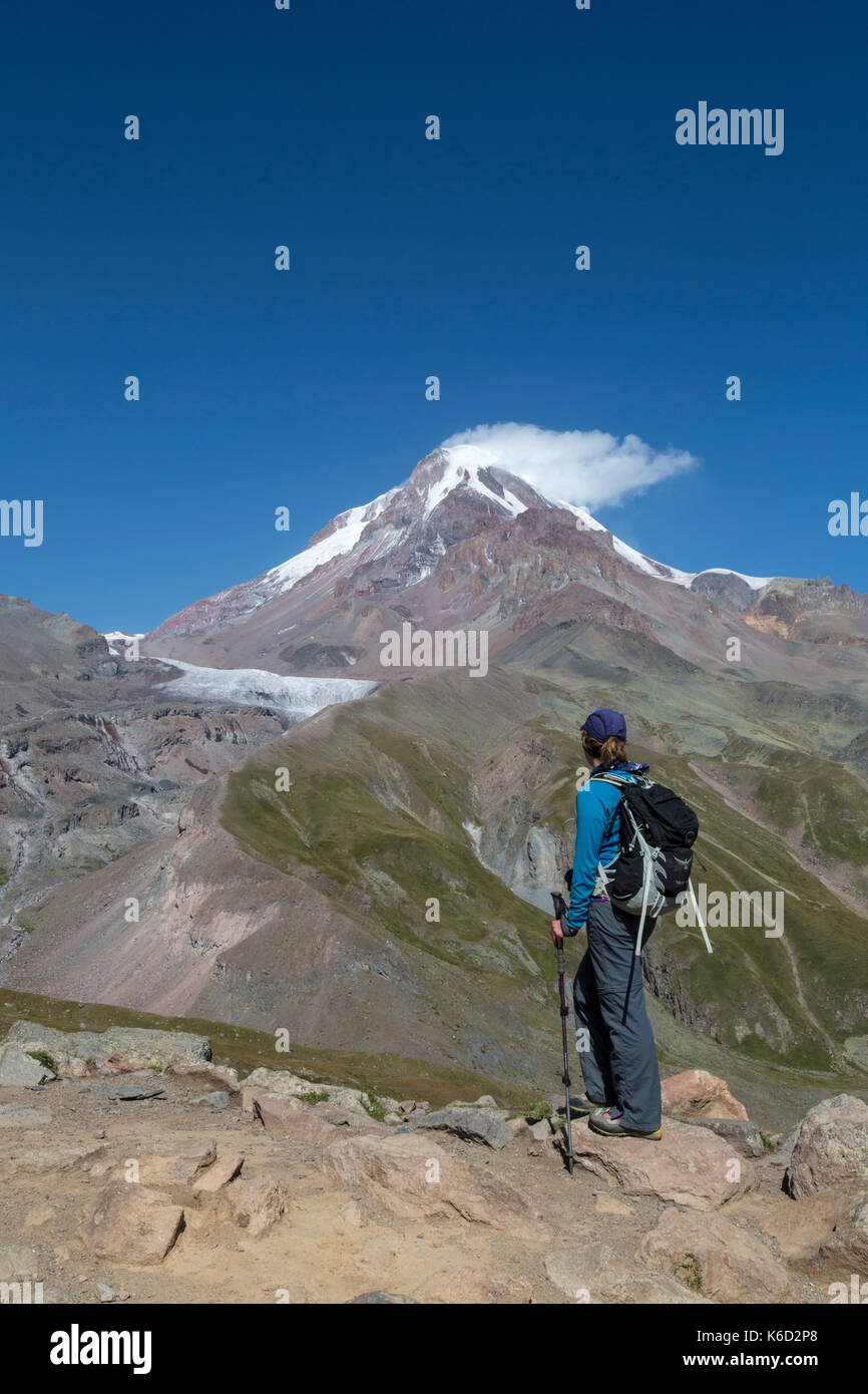 Female hiker looking up towards the peak of Mount Kazbek in Georgia ...