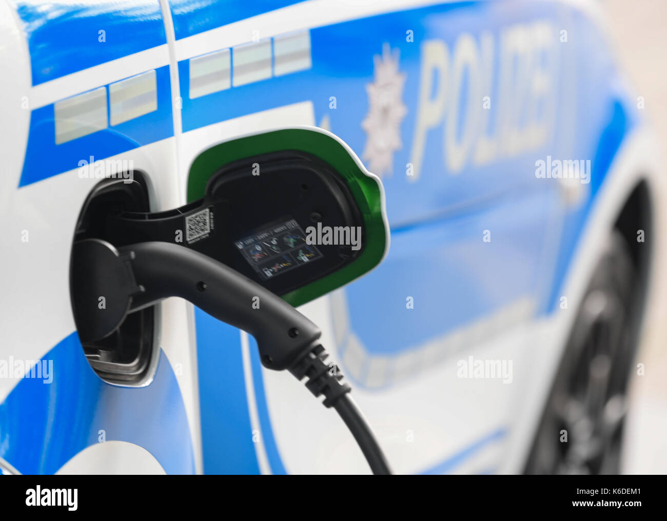 A charging chord is plugged into an electric police car at the stand of ...