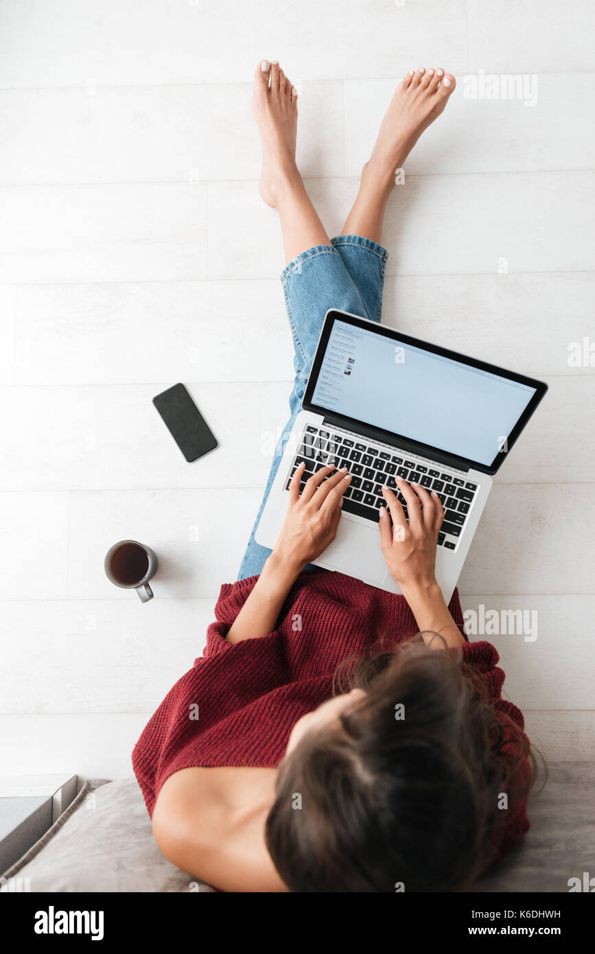 Top view of a young woman holding laptop computer on her lap while ...