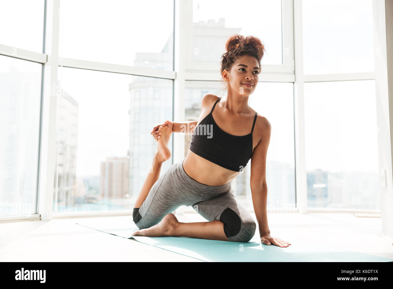 Concentrated african woman making difficult yoga exercise on floor at ...