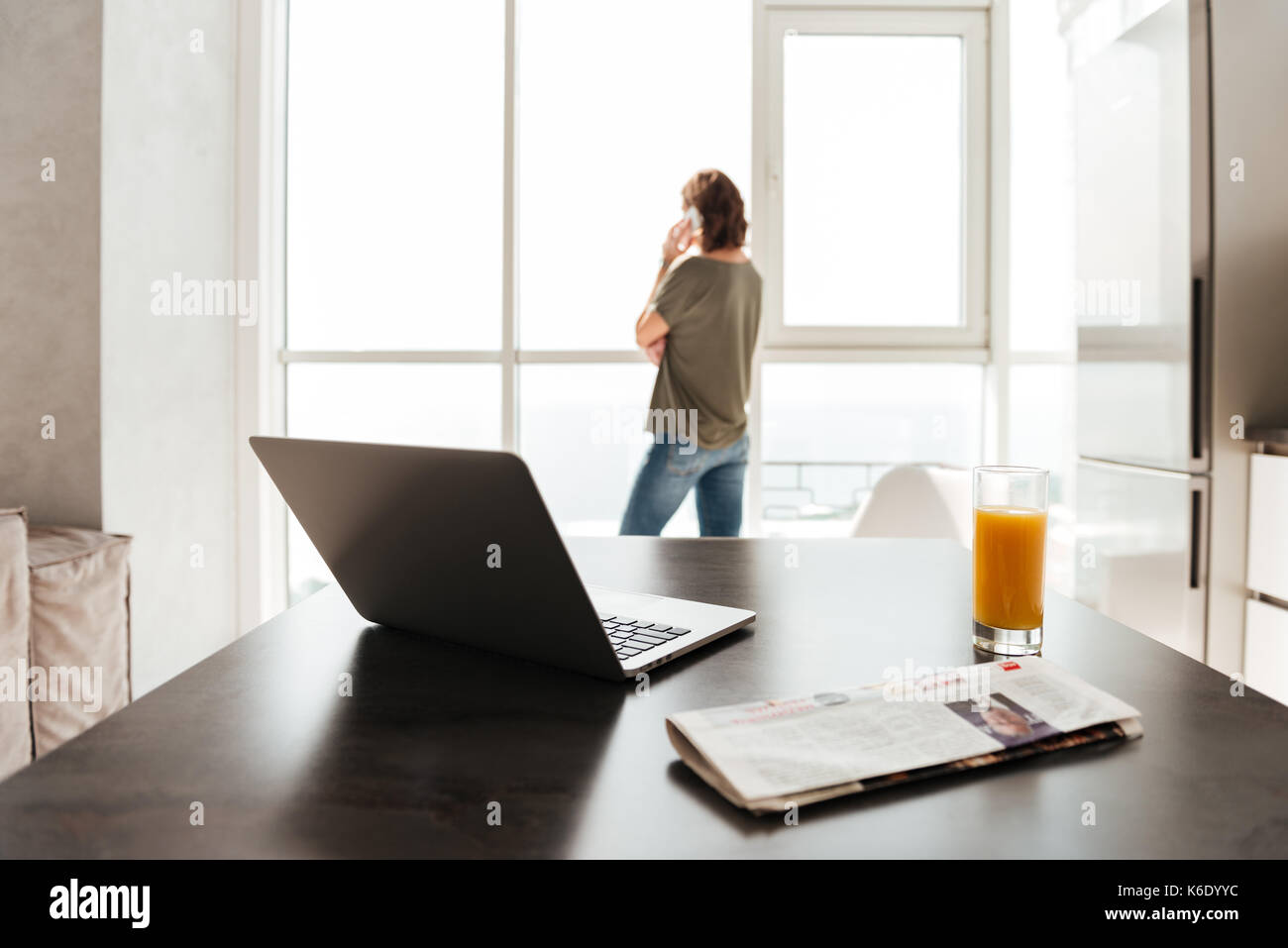 Photo of table with laptop computer, juice, newspaper and woman near ...