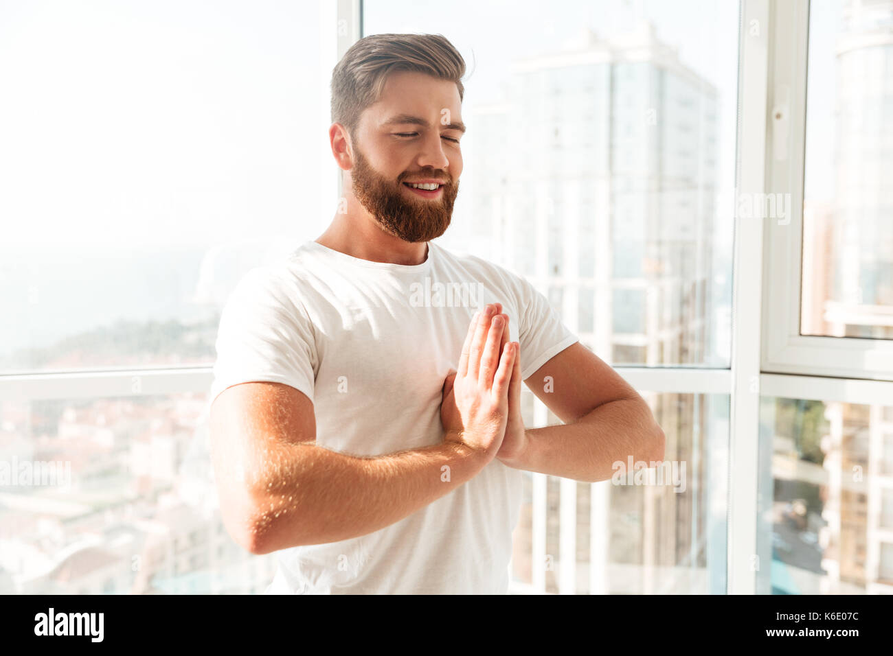 Side view of smiling bearded man meditation with closed eyes over ...