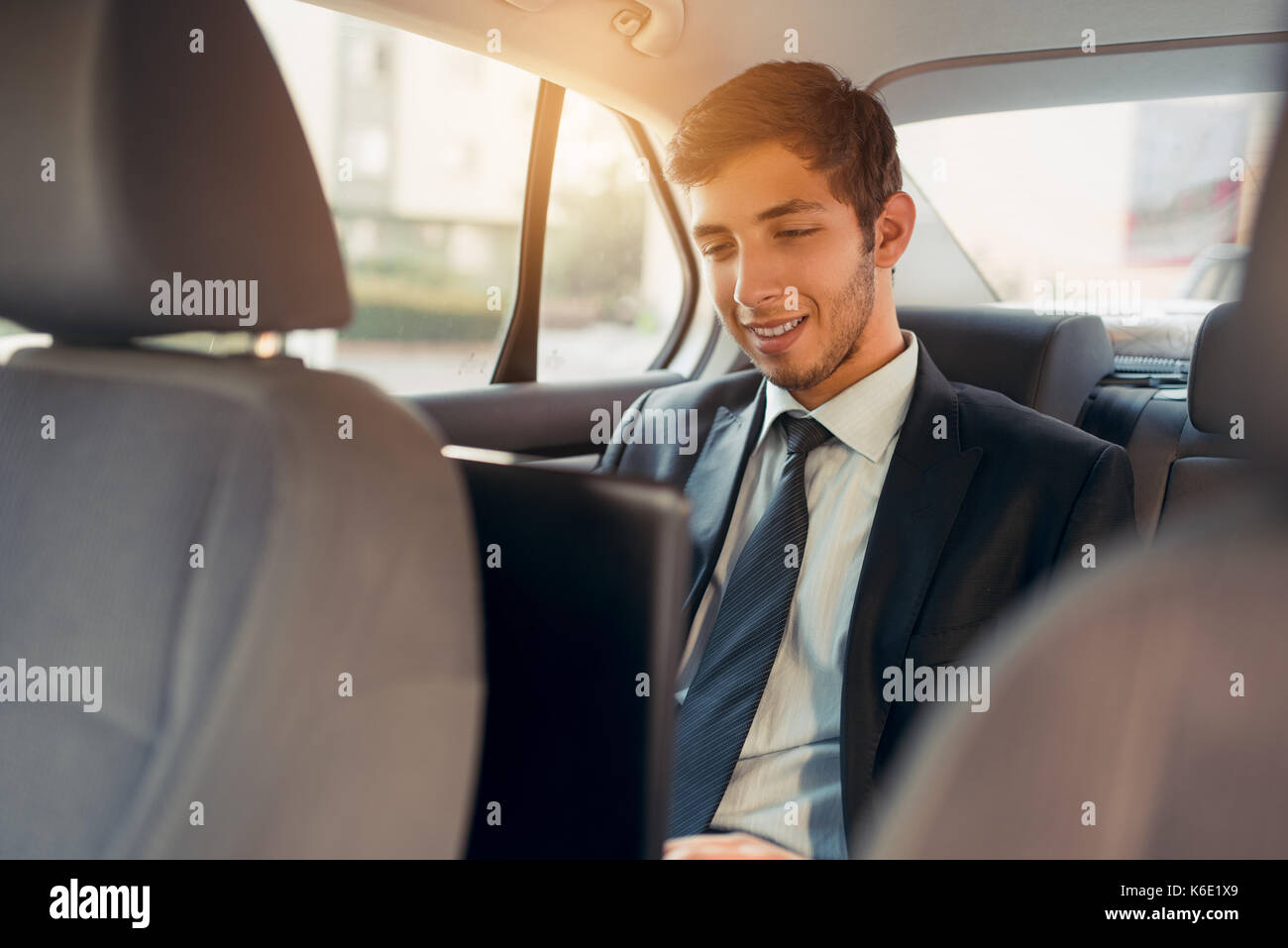 Businessman working while sitting in a car. Man beeing driven to work ...