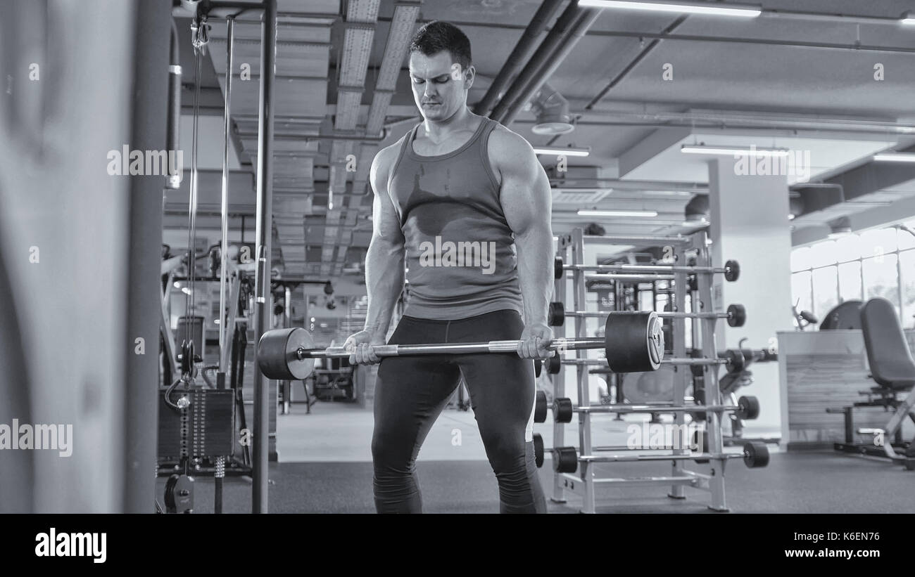 Bodybuilding in the gym - muscular man perform exercises with barbell ...