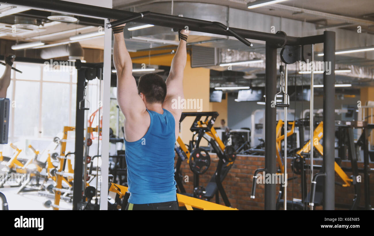 Male athlete - bodybuilder doing pull-up bar abdominal exercise in gym ...