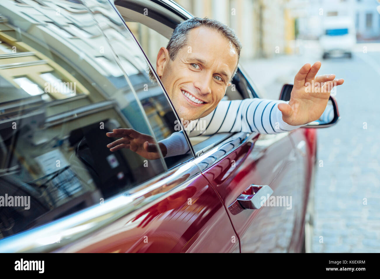 Cheerful positive man putting his hand of the car window Stock Photo ...