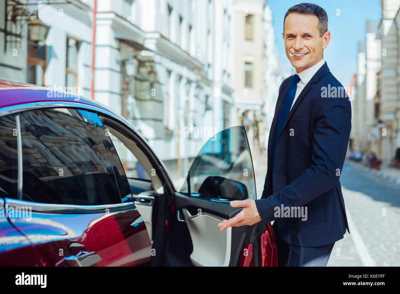 Joyful polite man pointing to the car seat Stock Photo - Alamy