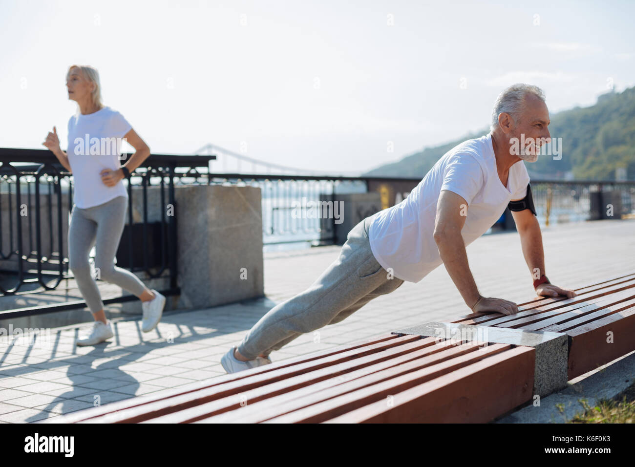 Senior man doing push-ups while his wife jogging Stock Photo - Alamy