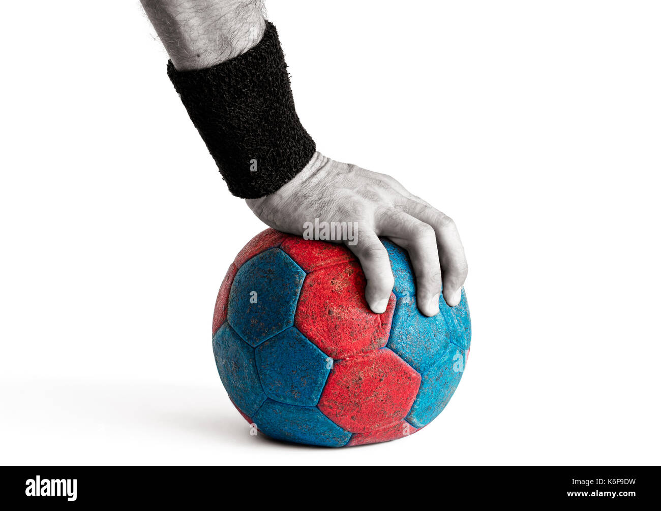 Man's hand pressing down on blue and red handball isolated on white ...