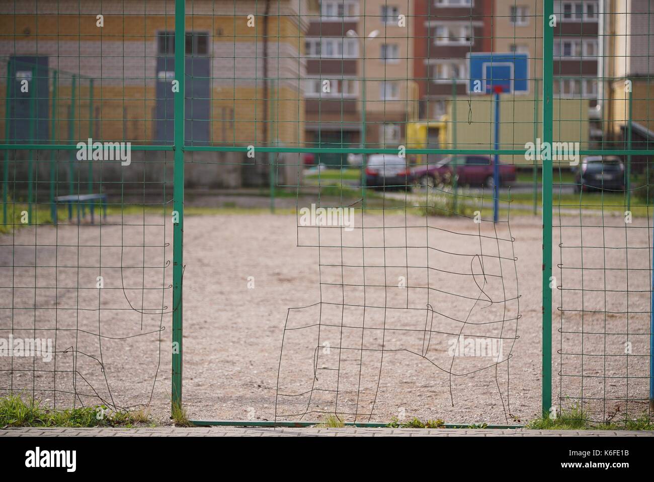 Broken steel mesh of metal fence of a basketball court in residential ...