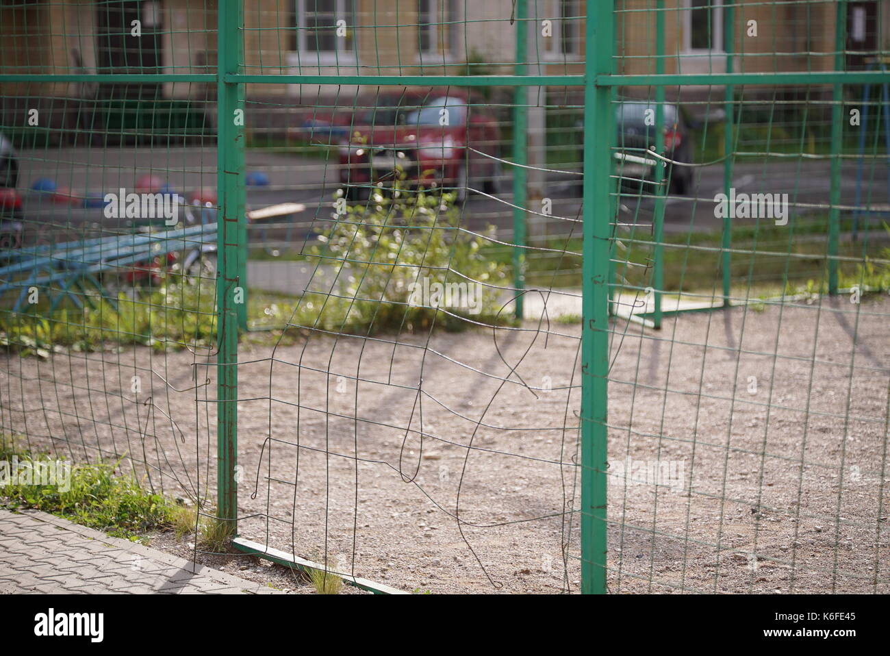 Broken steel mesh of metal fence of a basketball court in residential ...