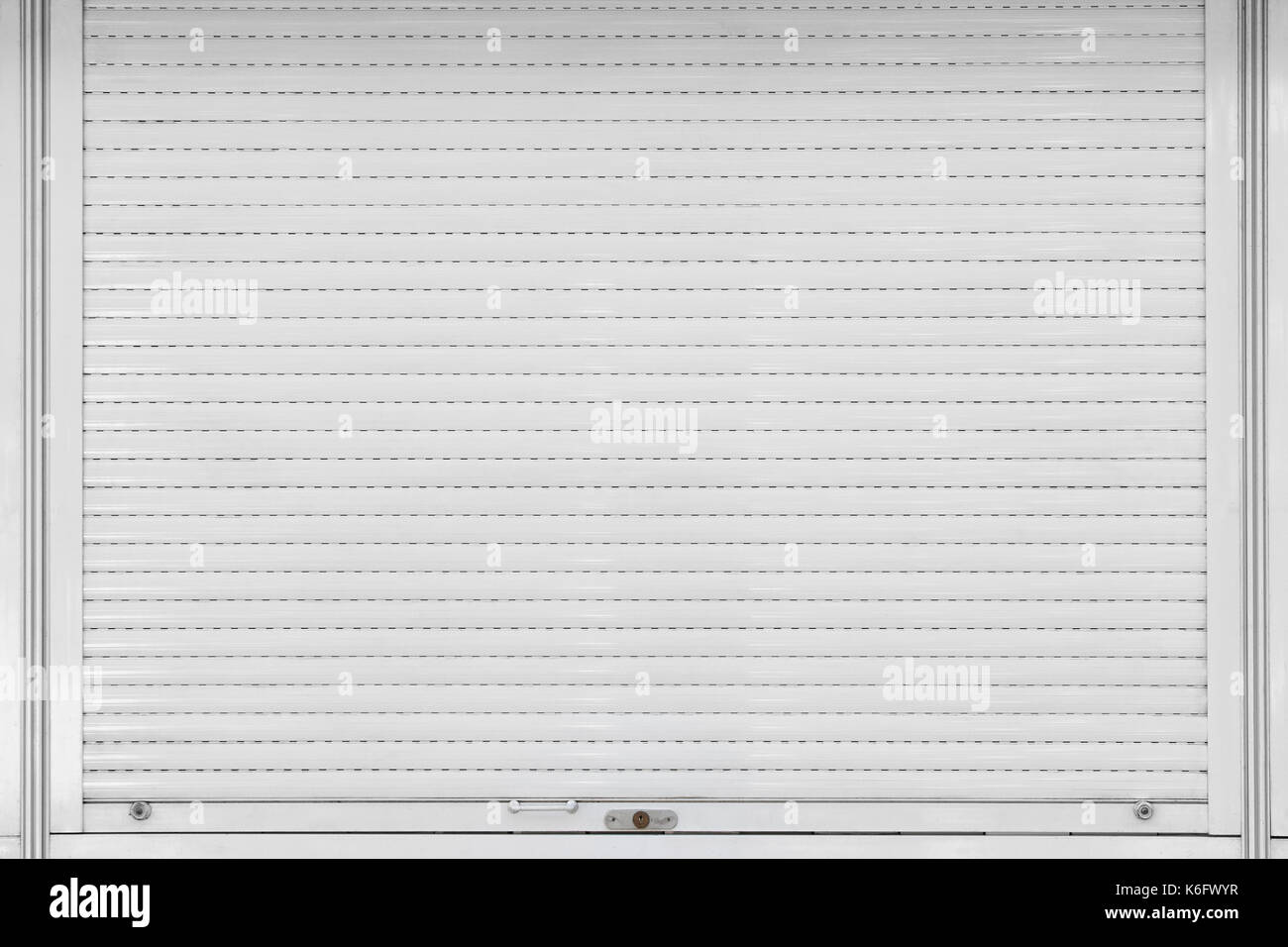 Closed and locked white rolling shutter. Security background ...