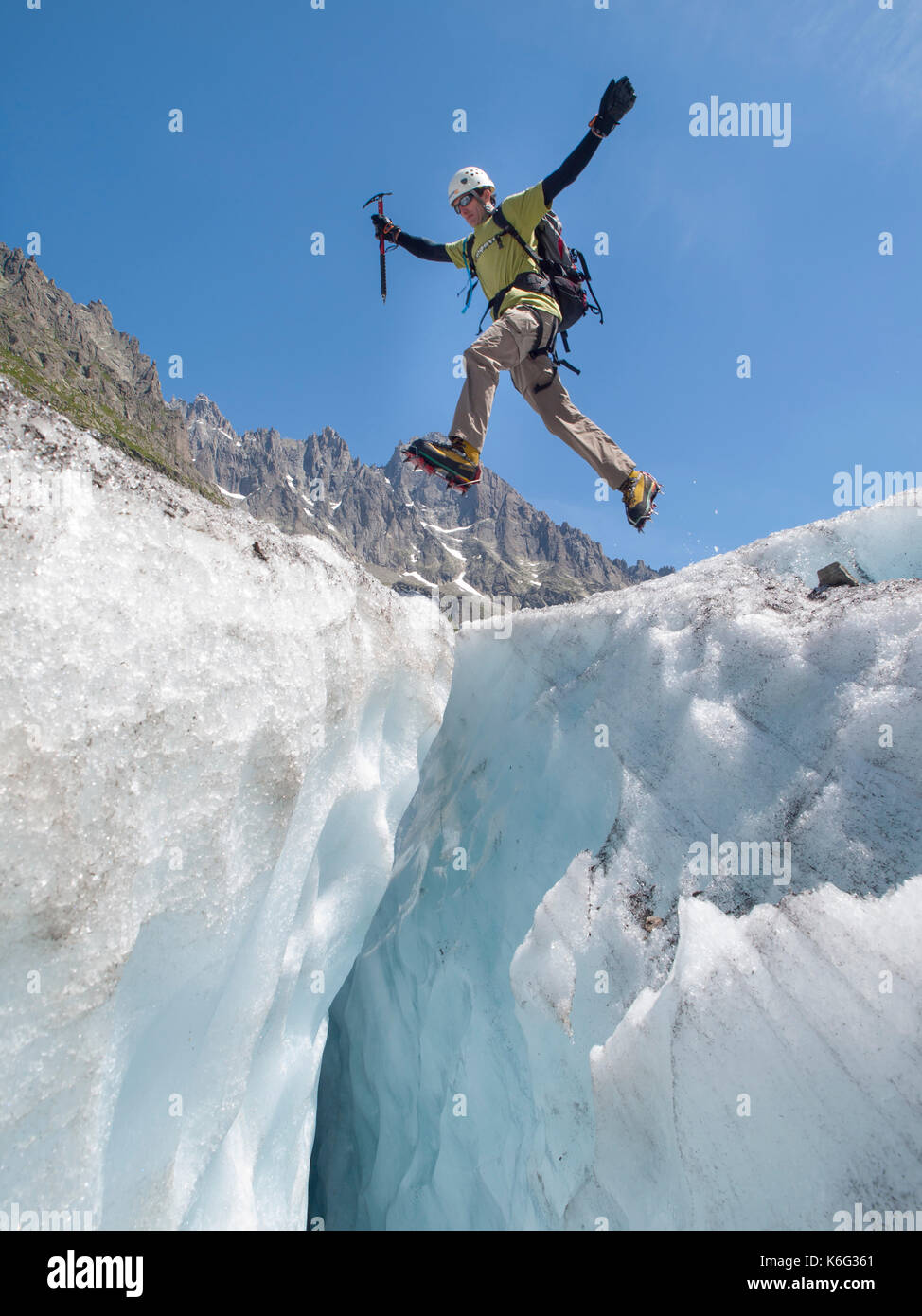 Mountain climber jumping over crevasse on Mer de Glace glacier, Mont ...