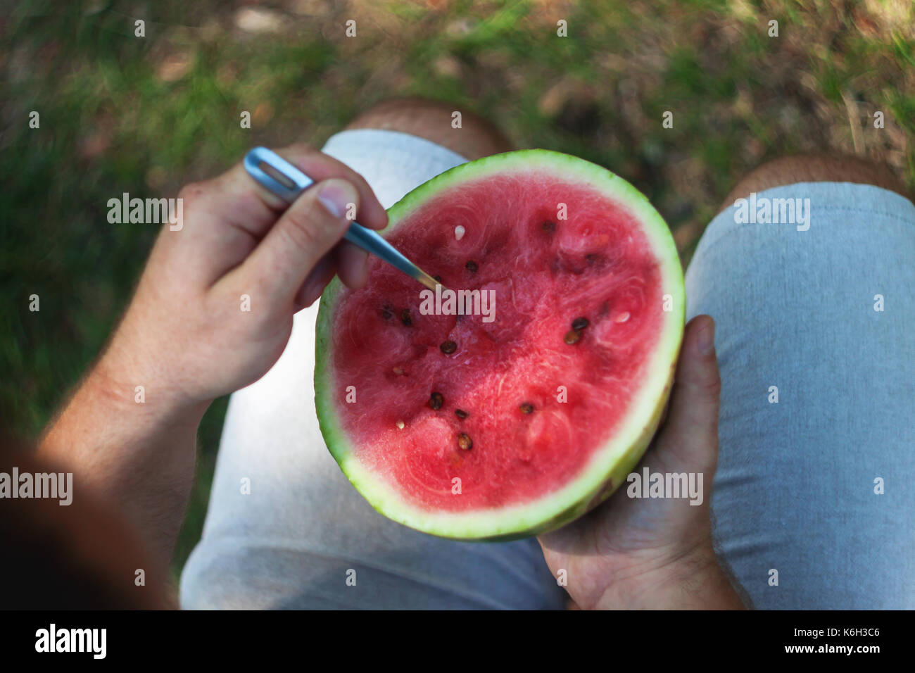 A young man is eating a watermelon with a spoon. The concept of healthy ...