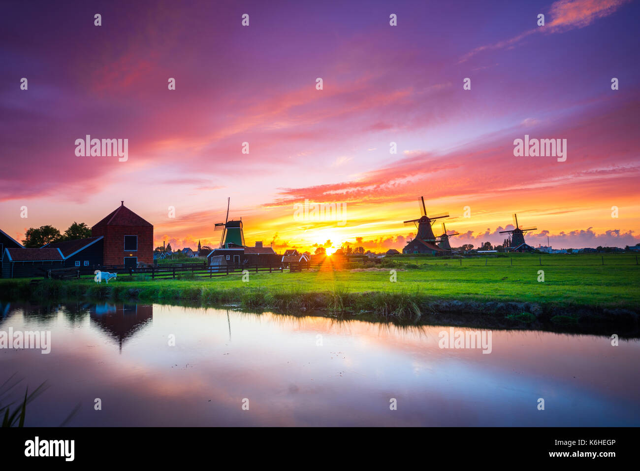 Traditional village with dutch windmills and river at sunset, Holland ...