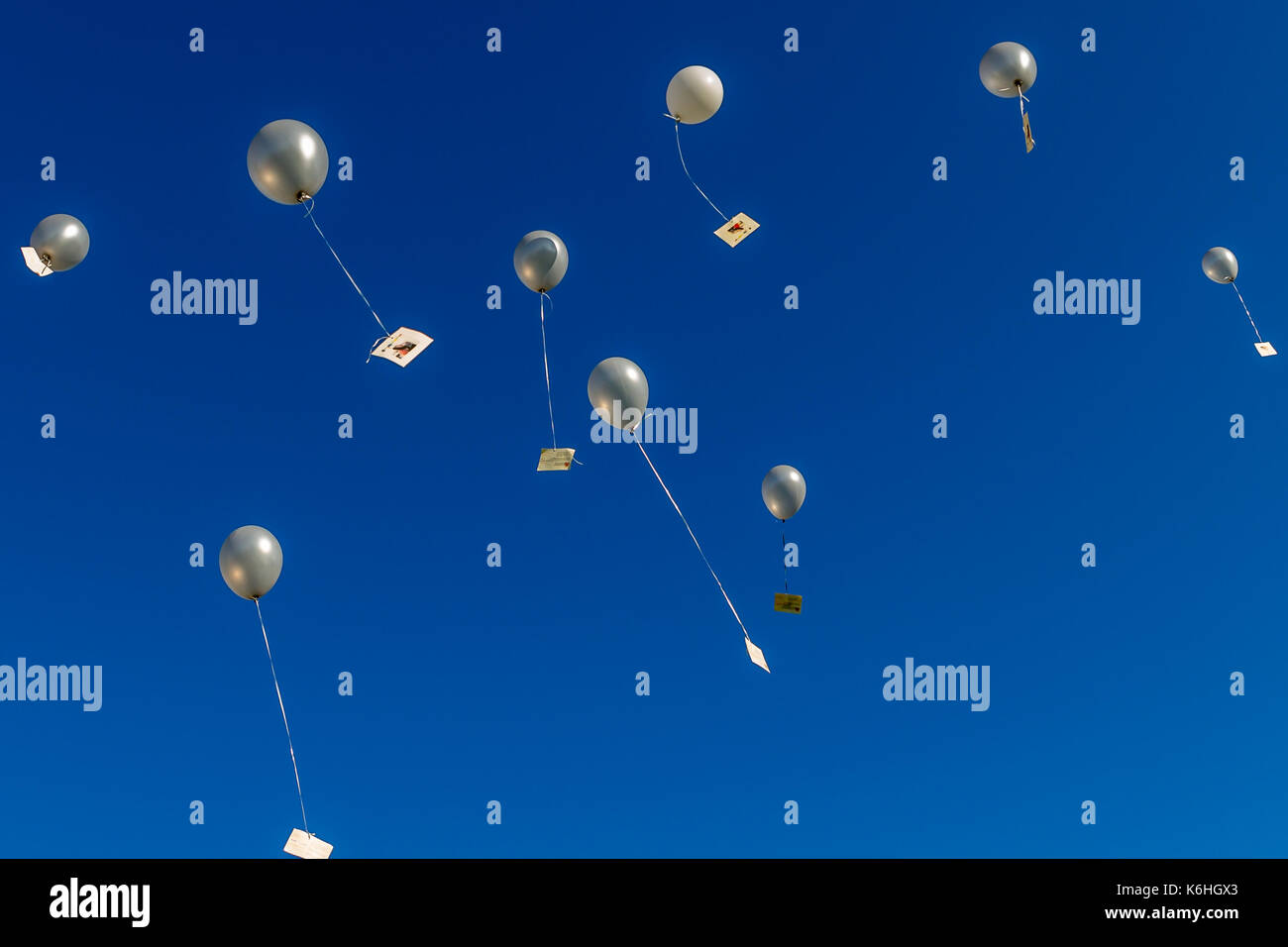 silver balloons going up in the blue sky Stock Photo - Alamy