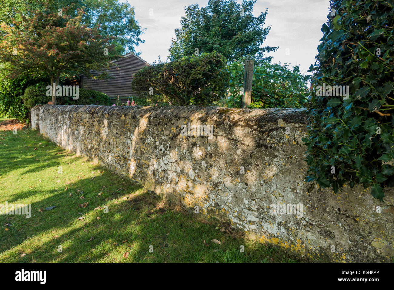 An attractive old stone boundary wall, in the dappled sunlight, with ...