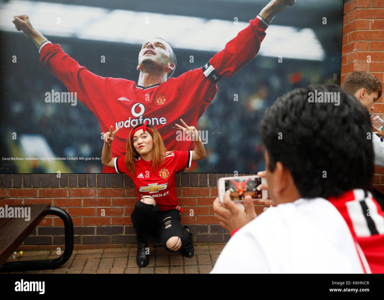A Manchester United fan poses in front of a picture of David Beckham ...