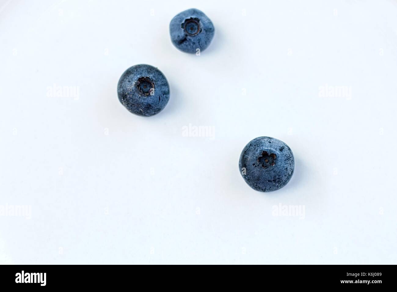 Three blueberries strategically placed for visual balance on a pure ...