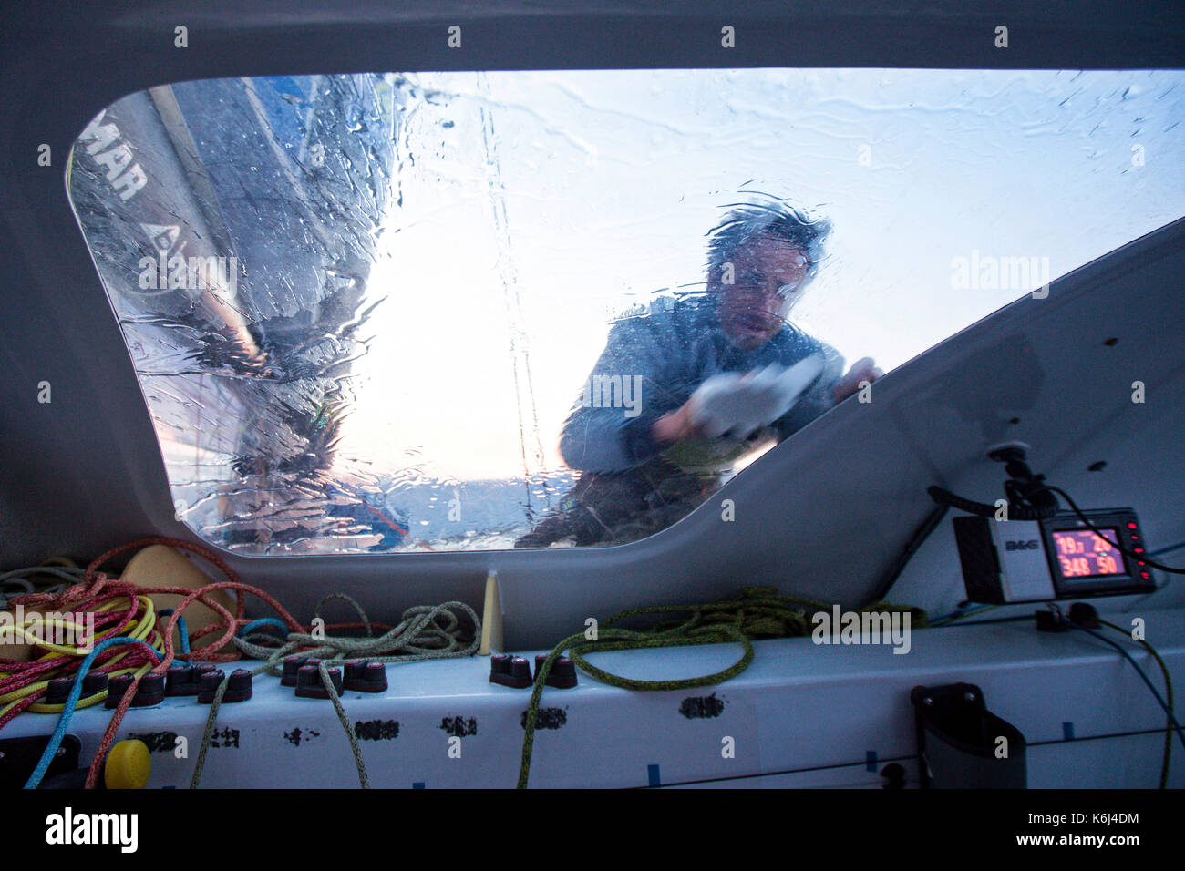 Sailor cleaning windows onboard trimaran, Atlantic Ocean, Brittany ...