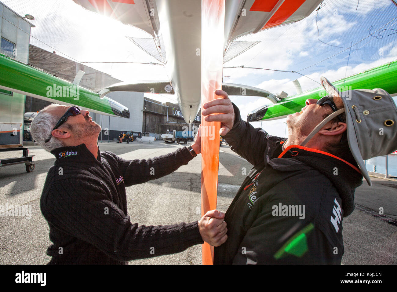 Two sailors installing central rudder on trimaran before being ...