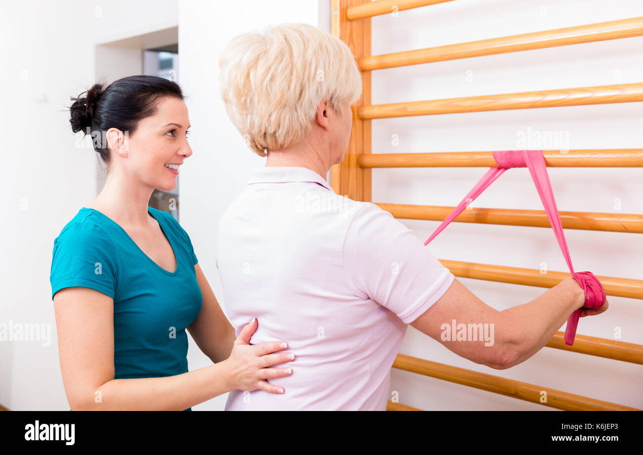 Physio assisting elderly woman during exercise with power band a Stock ...