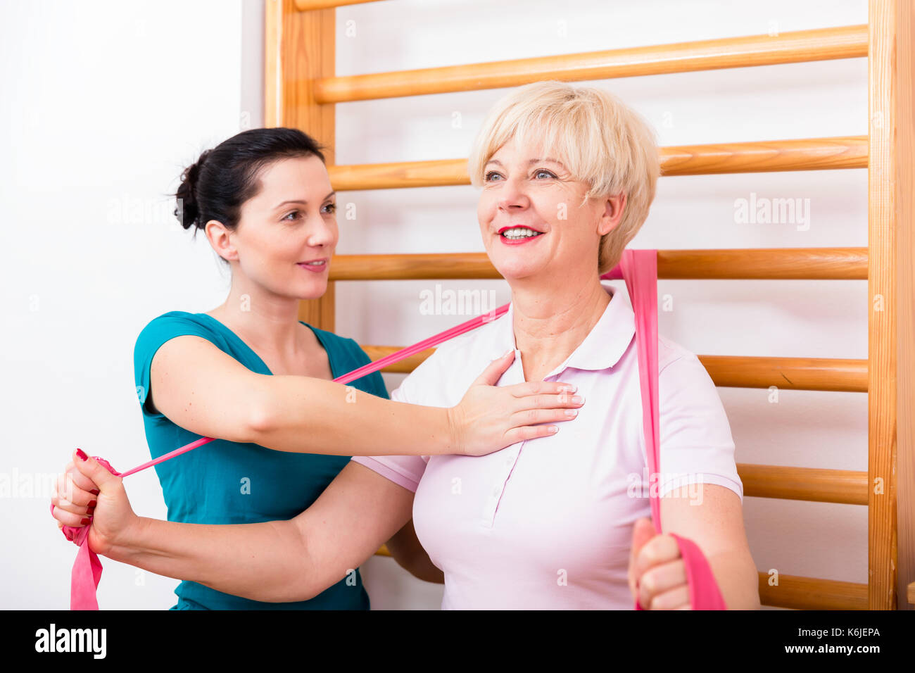 Physio assisting elderly woman during exercise with power band a Stock ...