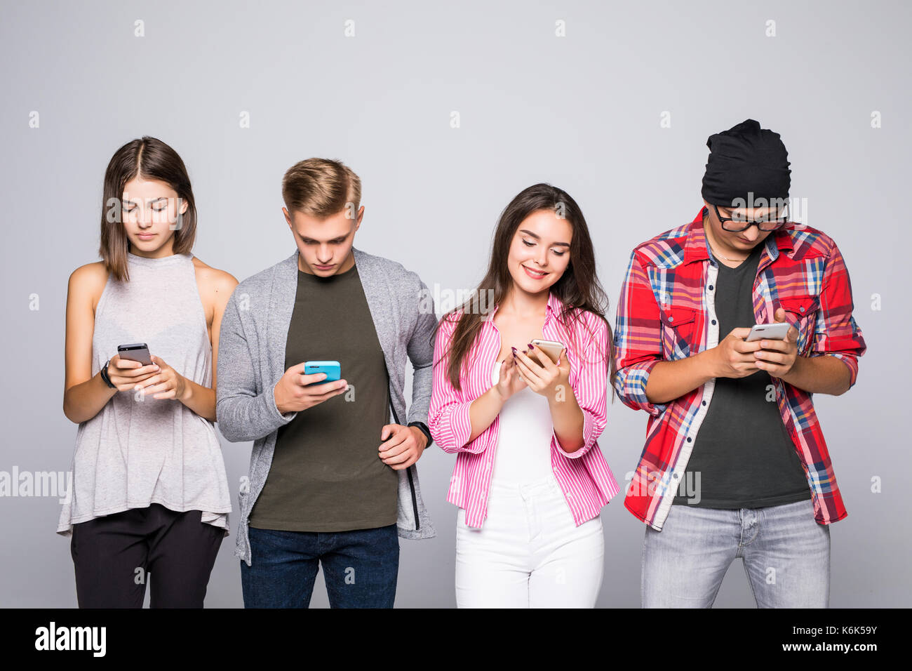 Diverse students standing and using modern gadgets isolated over grey ...