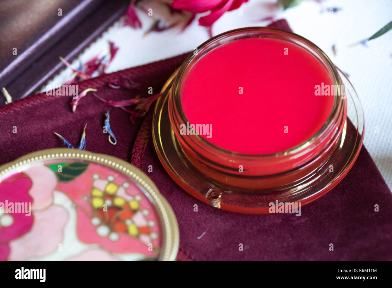 Red lip balm with flower detail on a white background Stock Photo - Alamy