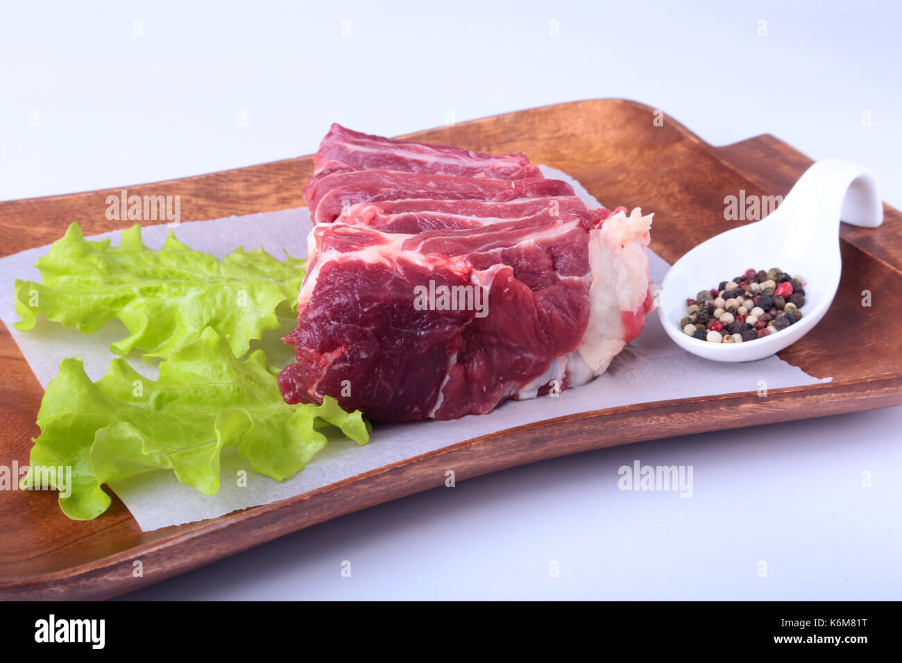 Raw beef edges, lettuce leaf and spices on wooden desk isolated on ...
