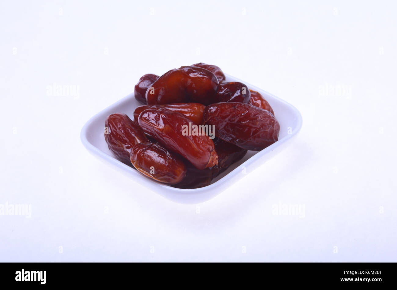Delicious dried organic dates on bowl isolated over white background ...