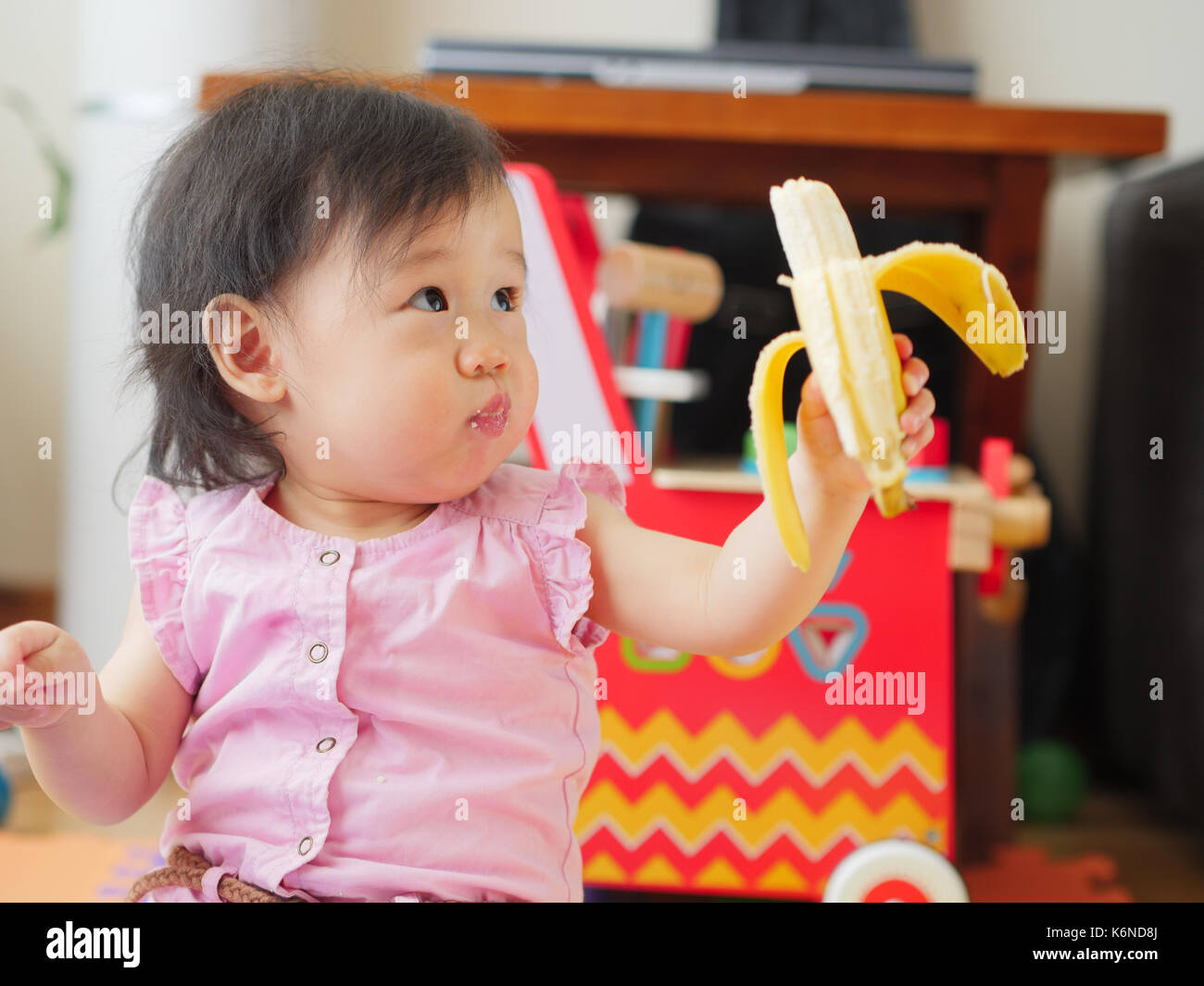 baby girl eating banana at home Stock Photo - Alamy