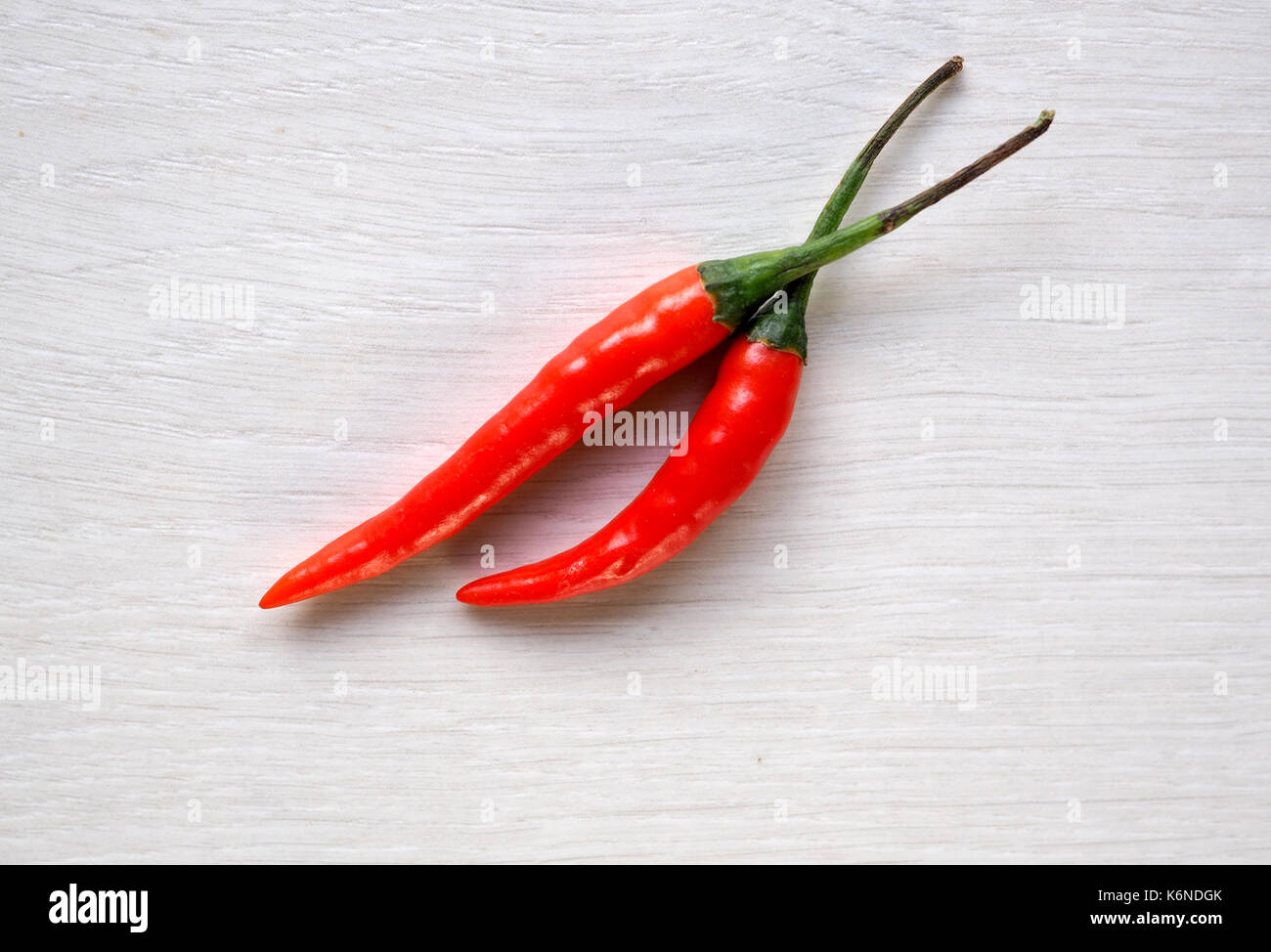 Two chilli peppers on white wood background Stock Photo - Alamy
