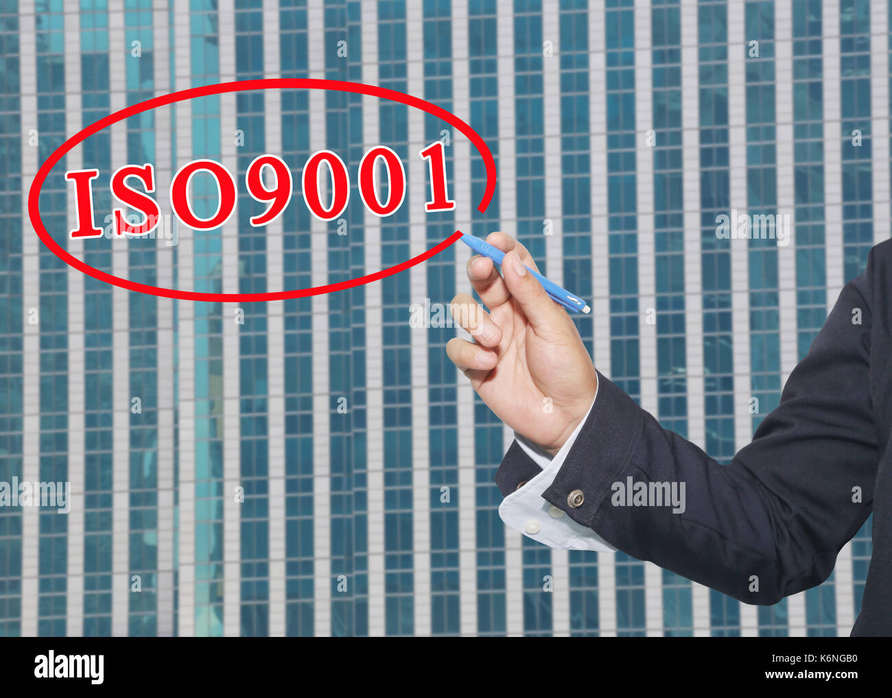 hand of a business man use a pen write text system ISO 9001 on glass ...