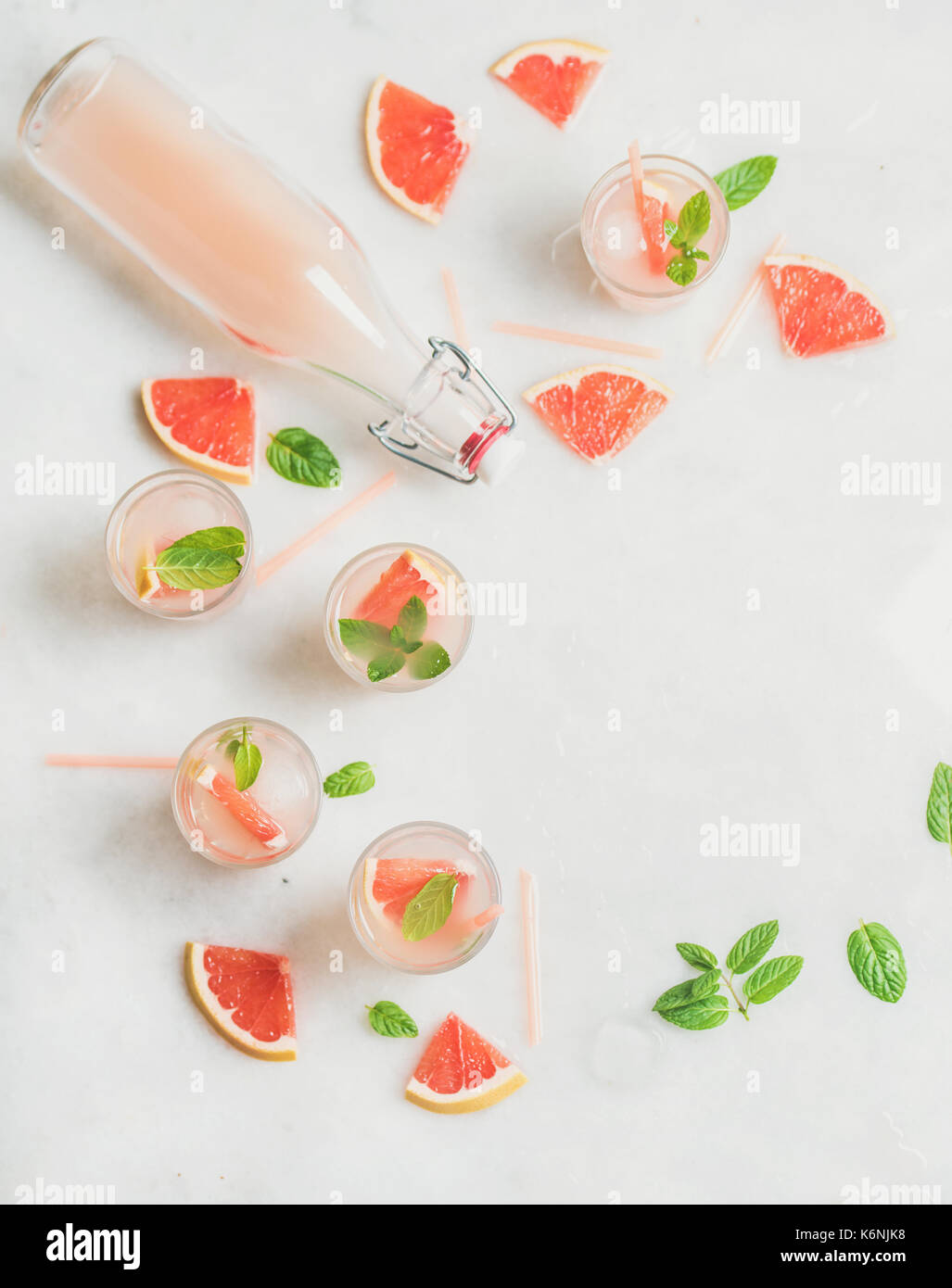 Cold refreshing alcohol cocktail with grapefruit in glasses and bottle ...