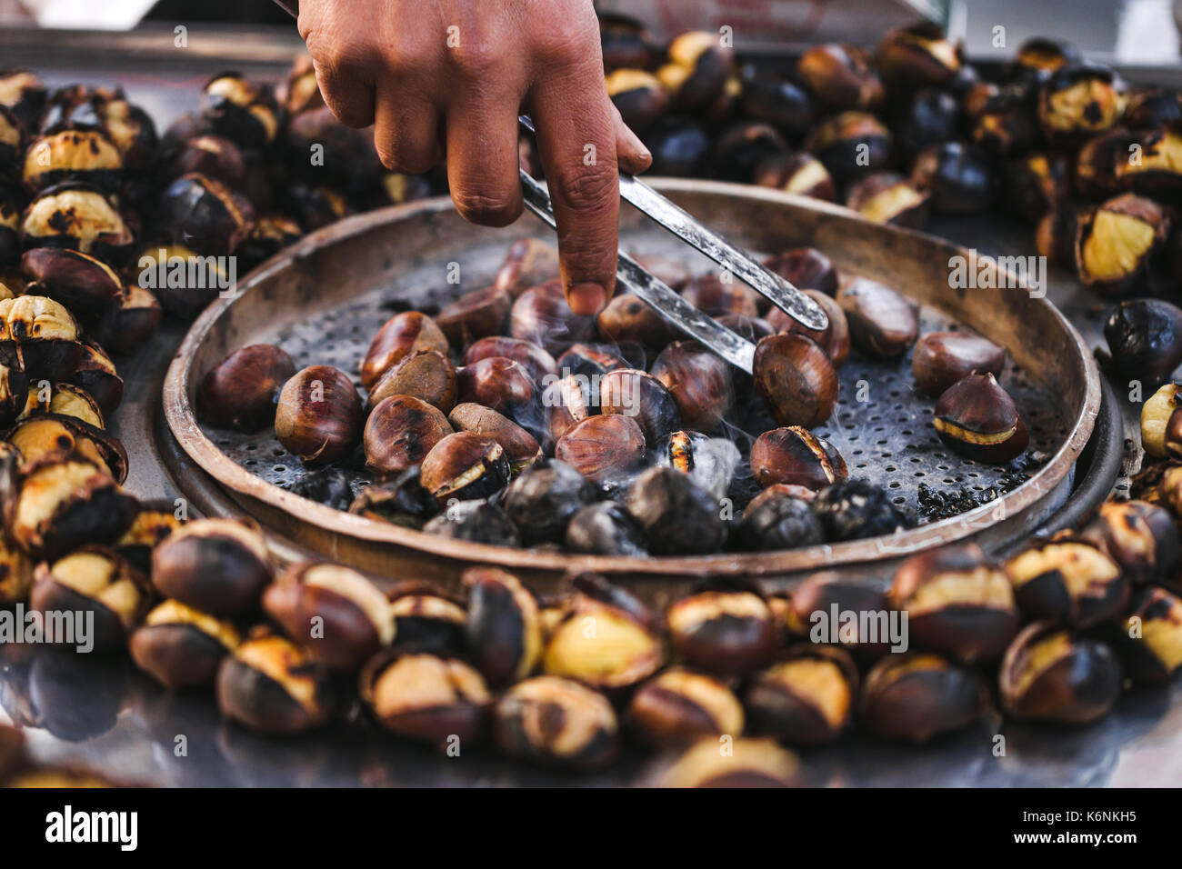 Man preparing roasted chestnuts, cooking outdoors. Street food in ...