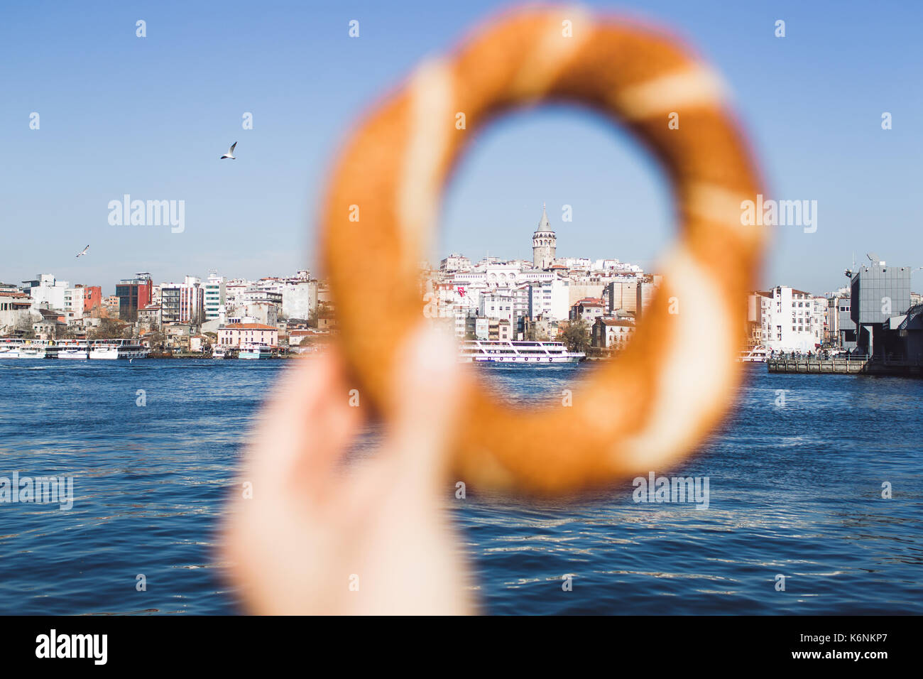 Woman hand holding a traditional Turkish simit on sea background and ...