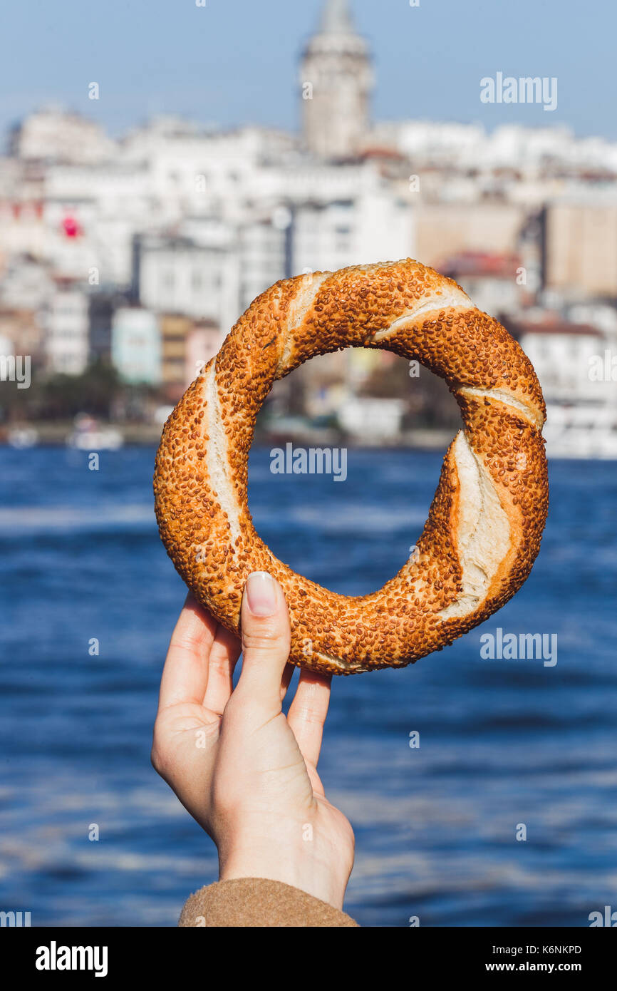 Woman hand holding a traditional Turkish simit on sea background and ...