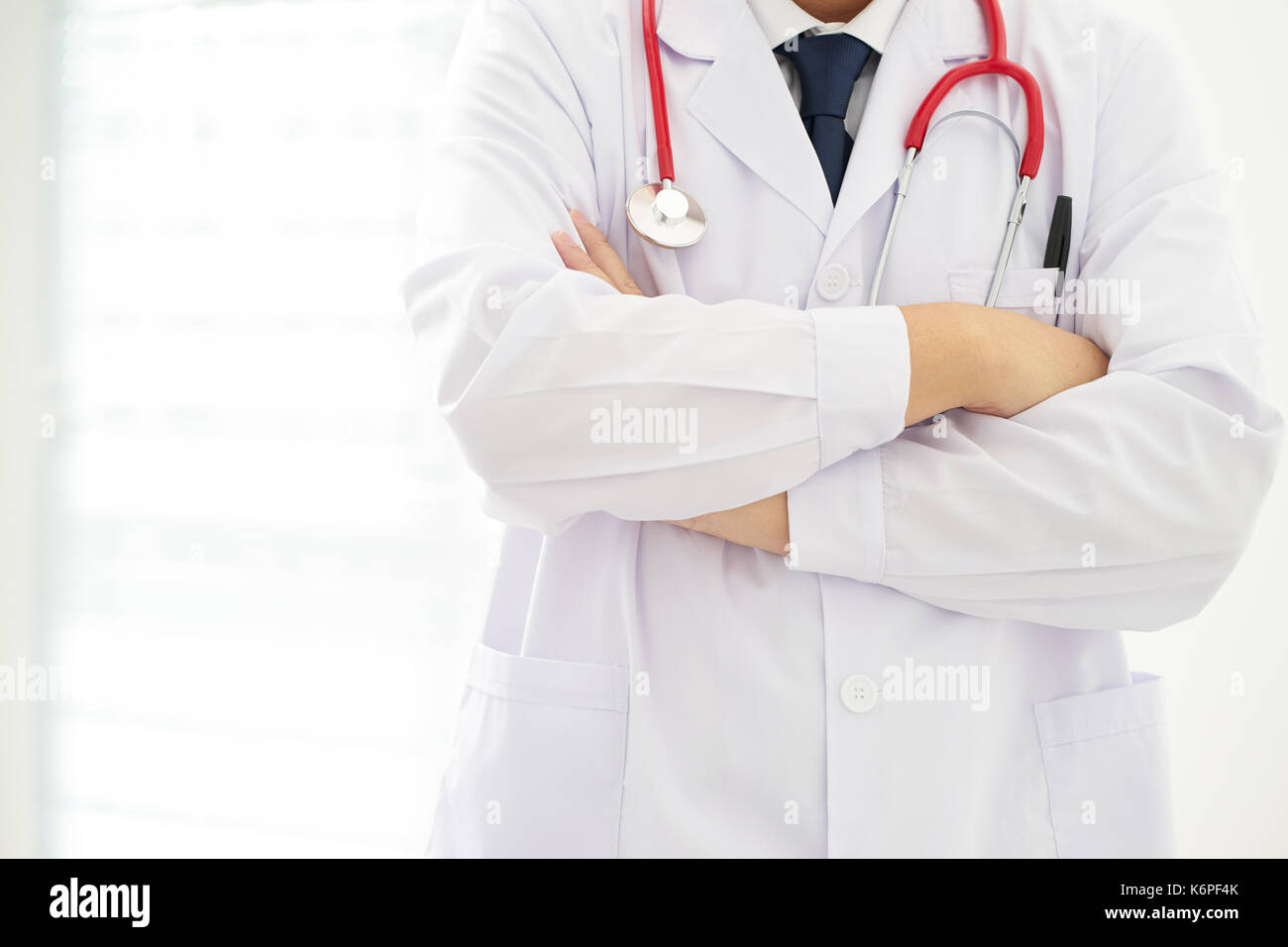 Unknow doctor posing with arms crossed in the office, he is wearing a ...